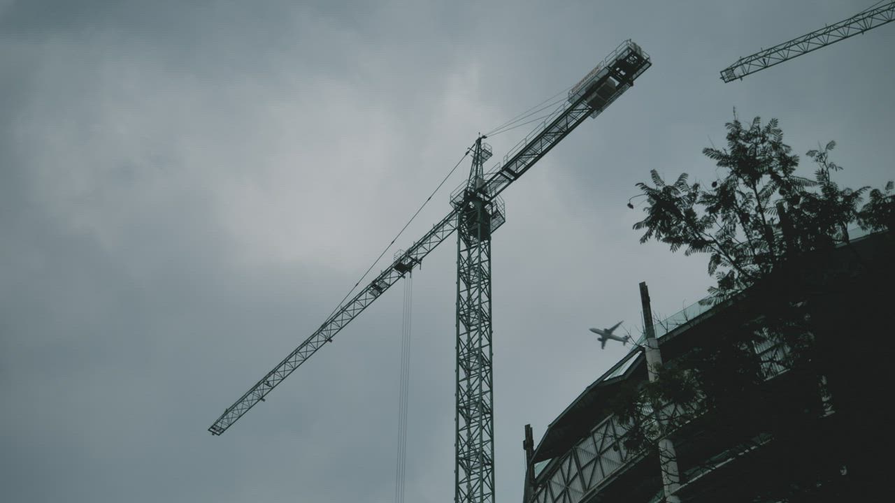 Construction crane with an airplane flying past - Free Stock Video
