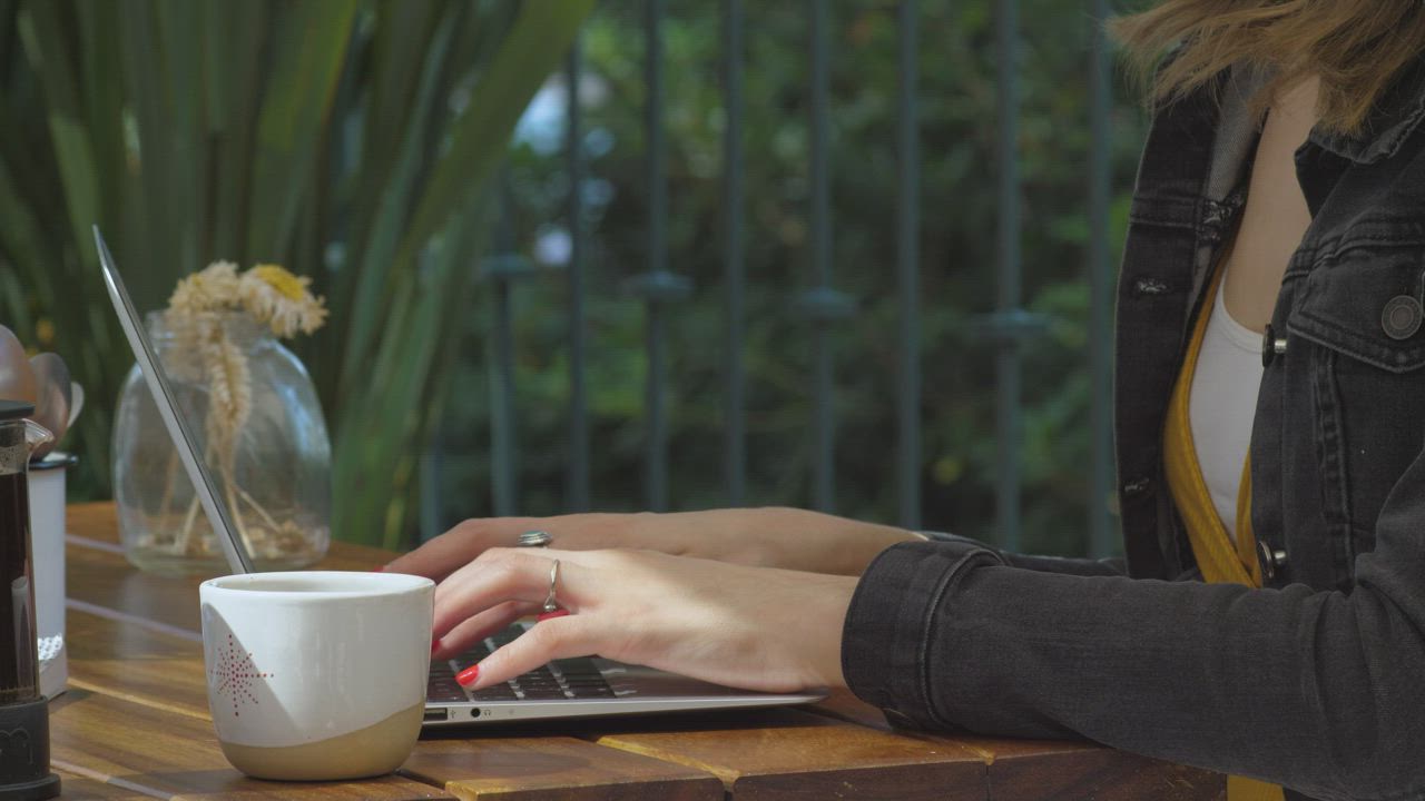 Woman typing on her laptop in a coffee shop - Free Stock Video