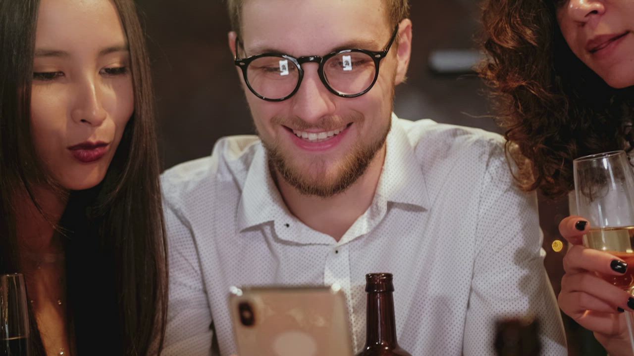 Happy friends looking at photo in a bar - Free Stock Video