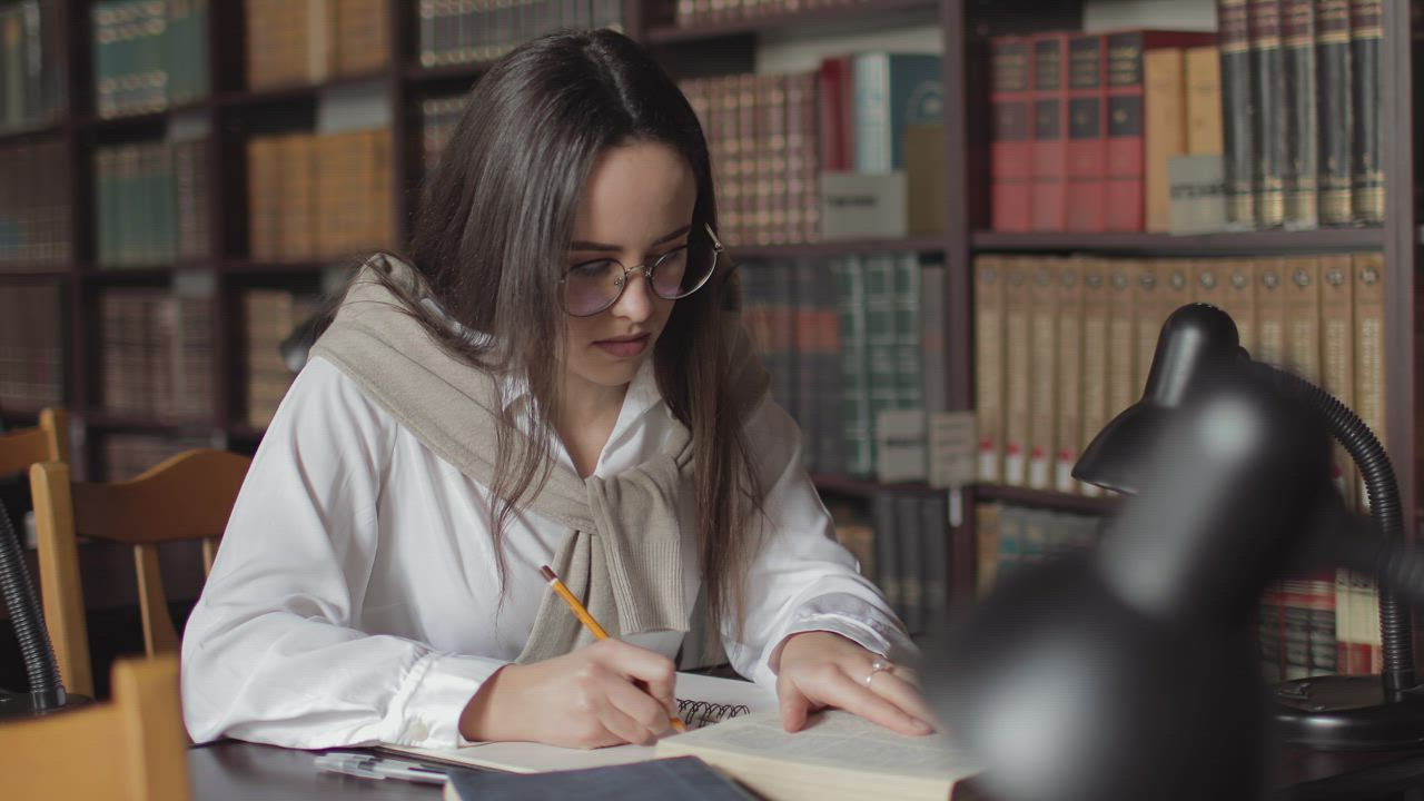 Woman writing her homework in the library - Free Stock Video