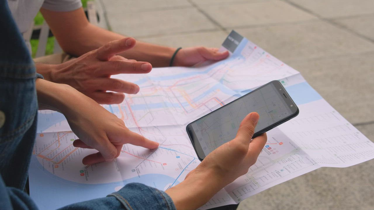 Two people sitting on a bench looking at maps of the area - Free Stock ...