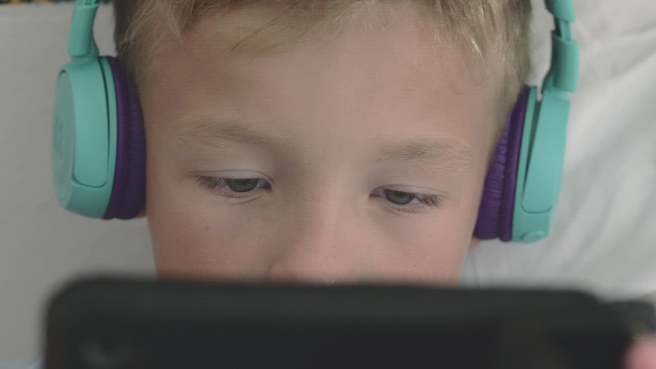 Boy playing games on a small tablet - Free Stock Video