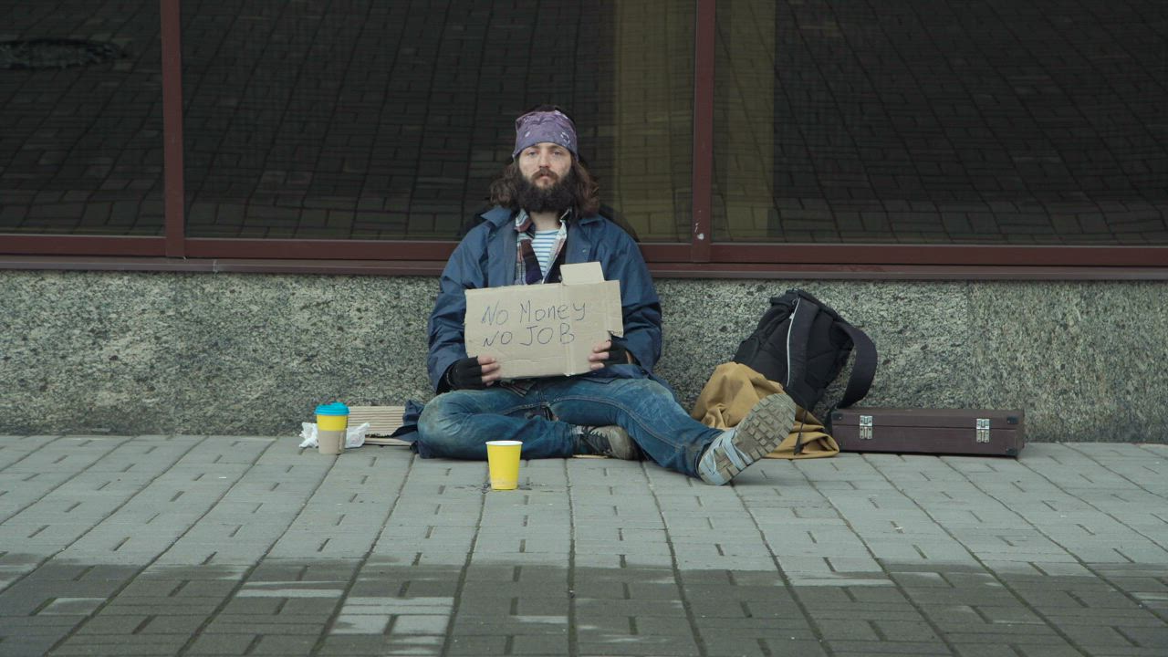 Homeless with cardboard sign sitting on the street - Free Stock Video