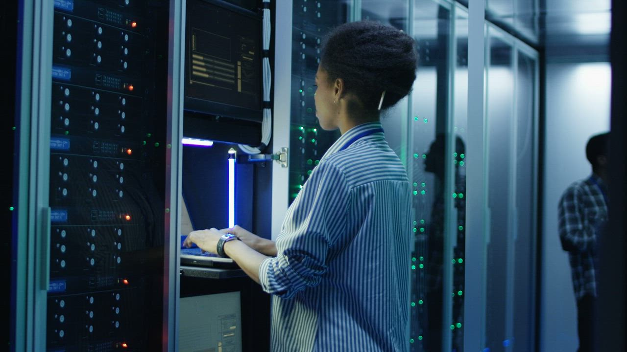 A woman working with a computer in the server room - Free Stock Video