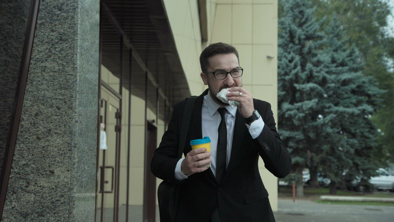 A business man is eating while walking - Free Stock Video