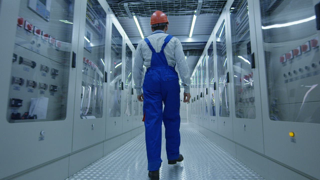 Worker walking in industrial machine corridor - Free Stock Video