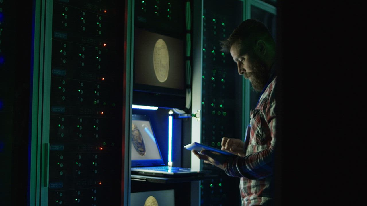 Man using a laptop in a dark room data center - Free Stock Video