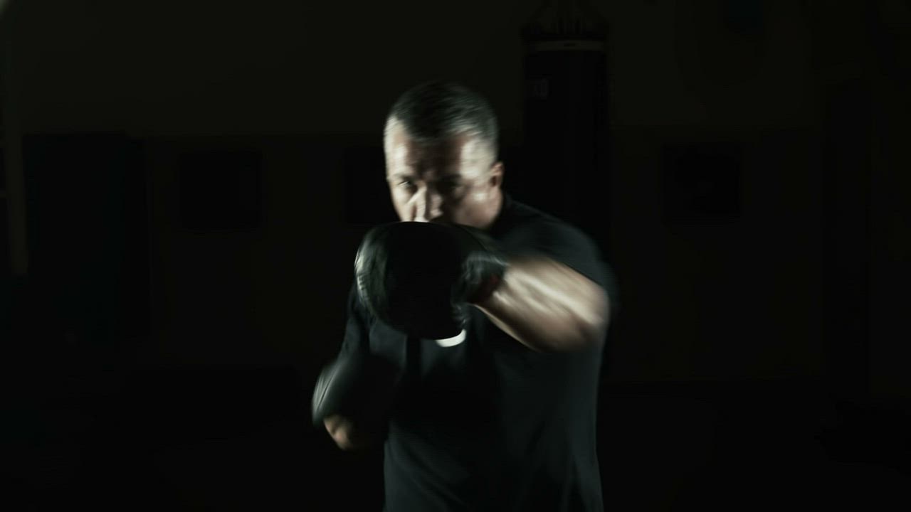 Old boxer training in a dark room - Free Stock Video