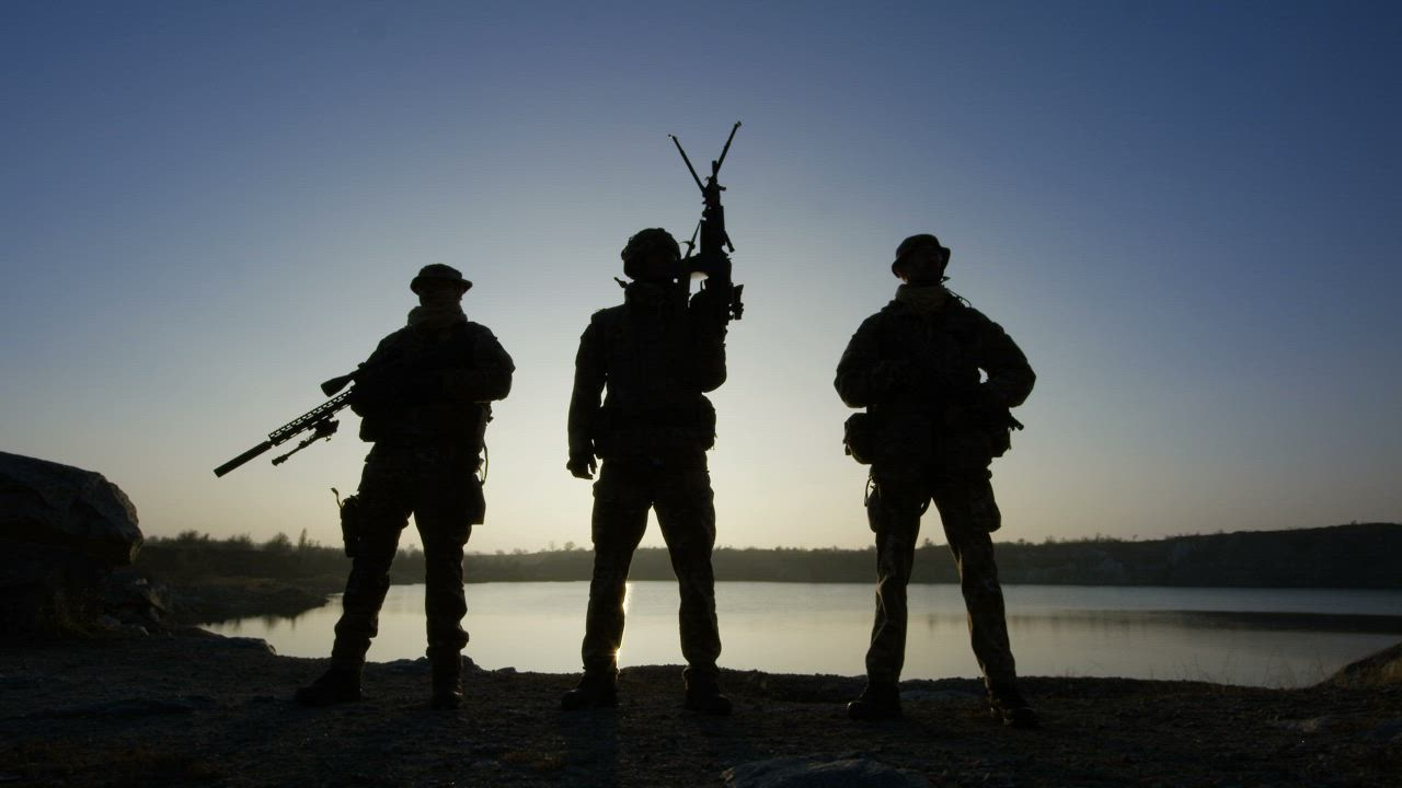 Soldier silhouettes posing with guns in the sunset - Free Stock Video
