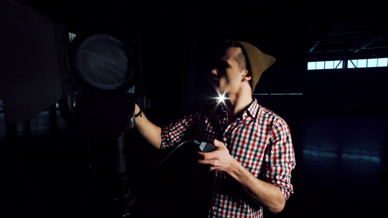 A young man turns on a studio light - Free Stock Video