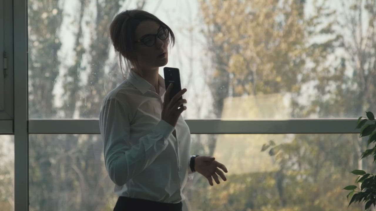 A woman talking on the phone near the window - Free Stock Video