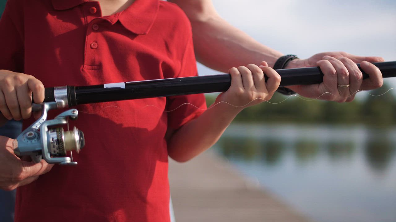 Teaching a kid how to fish in the lake - Free Stock Video