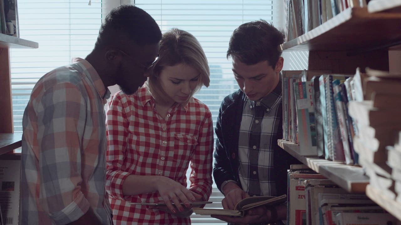 Students are discussing books in the library - Free Stock Video