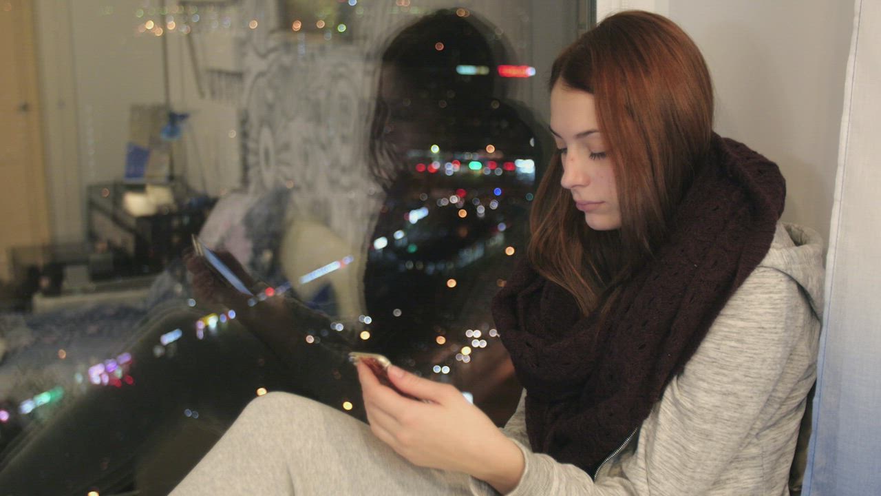 Using a smartphone by the window - Free Stock Video