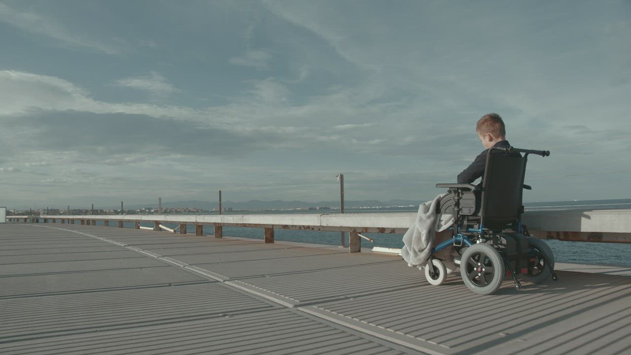 Boy in a wheelchair heading over a bridge - Free Stock Video