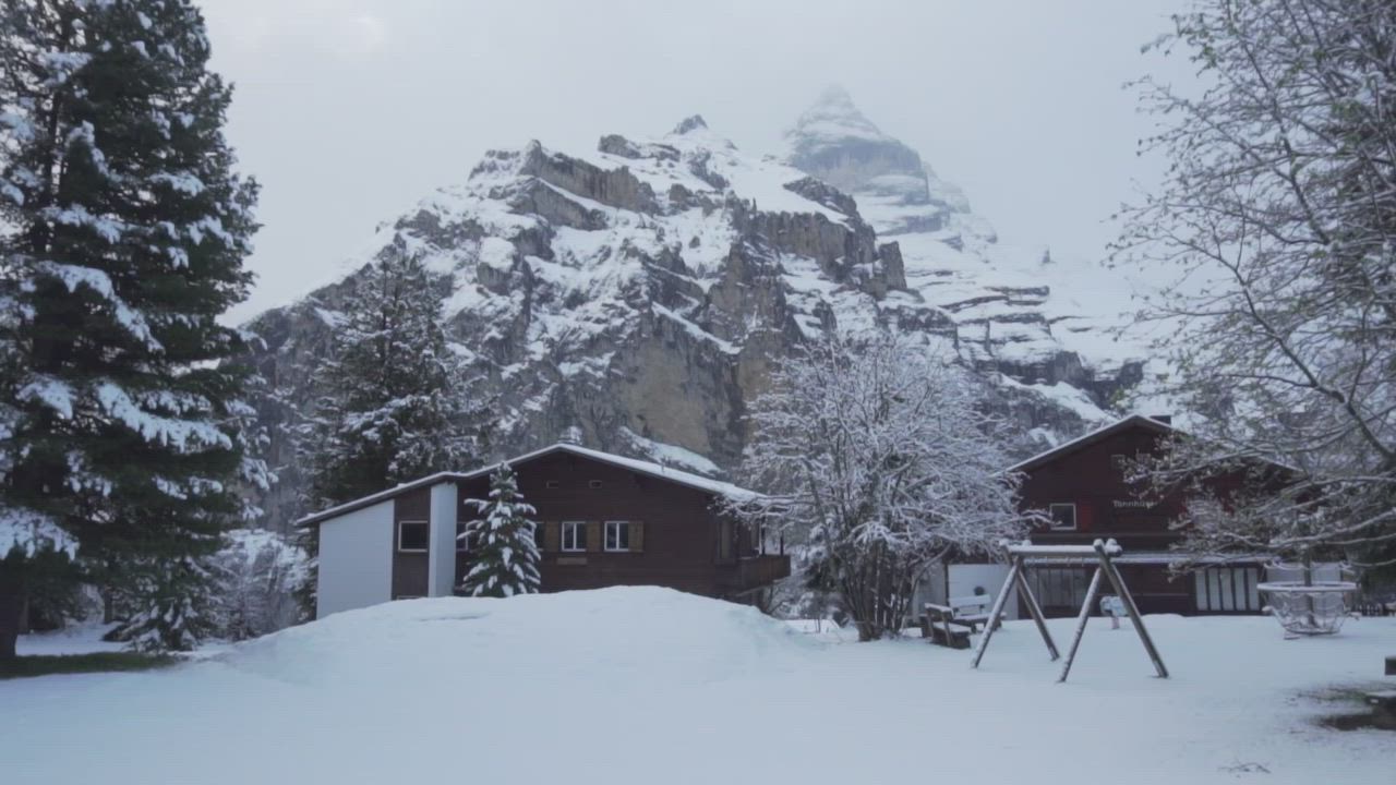 Snow covered cabins at base of a mountain - Free Stock Video