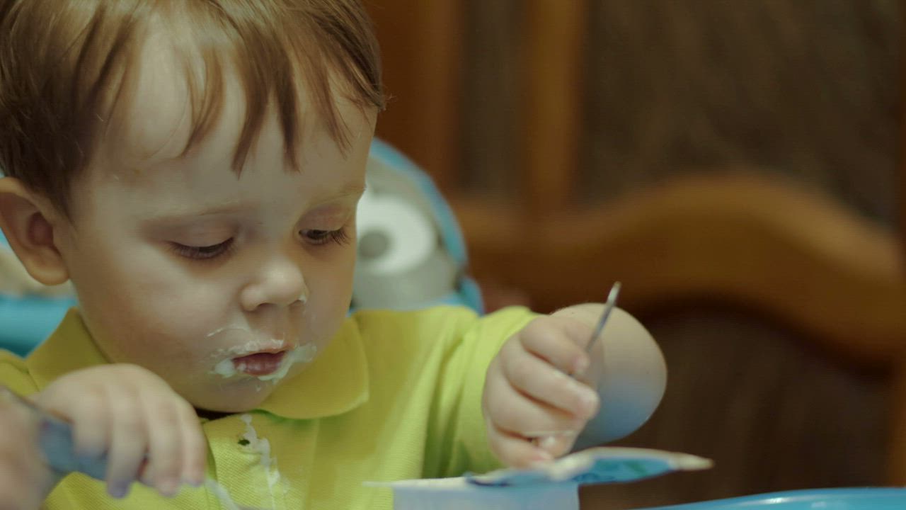 Young boy eating with two spoons - Free Stock Video