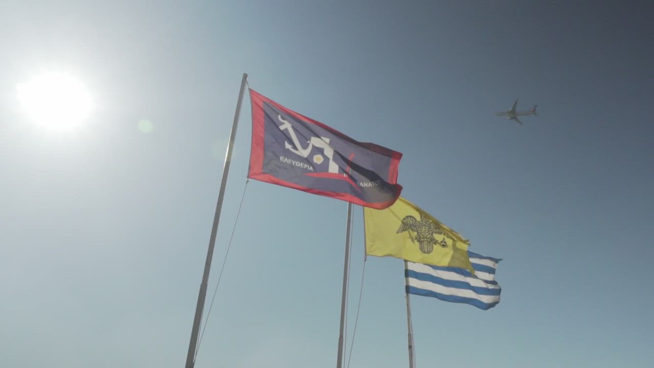 Plane flying past three flags - Free Stock Video