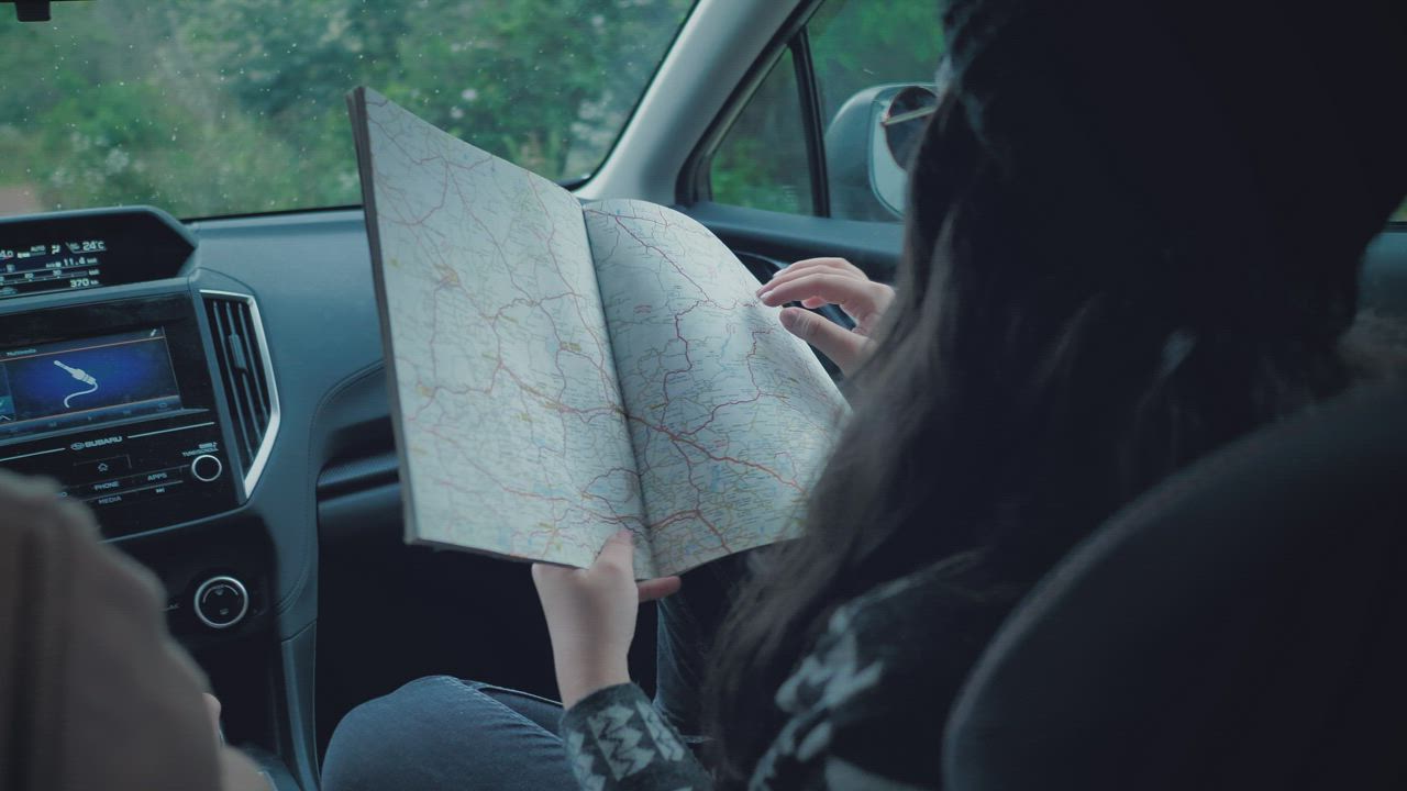 Couple of adventurers reading a map inside a car - Free Stock Video