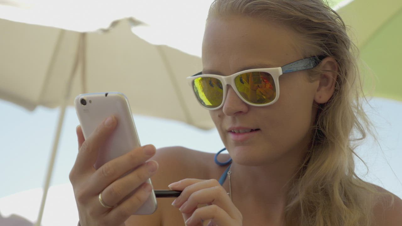 Texting while relaxing on the beach - Free Stock Video