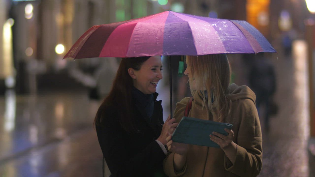 Friends standing under an umbrella - Free Stock Video