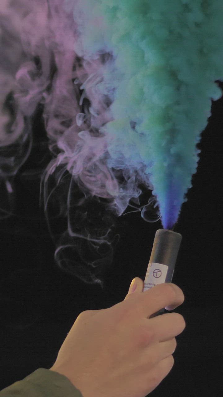 Hand holding a multicolored smoke bomb - Free Stock Video