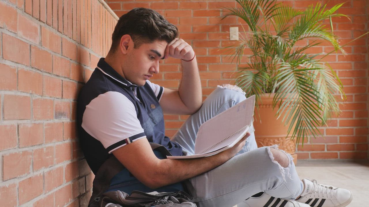 Frustrated student at his school studying his notes - Free Stock Video
