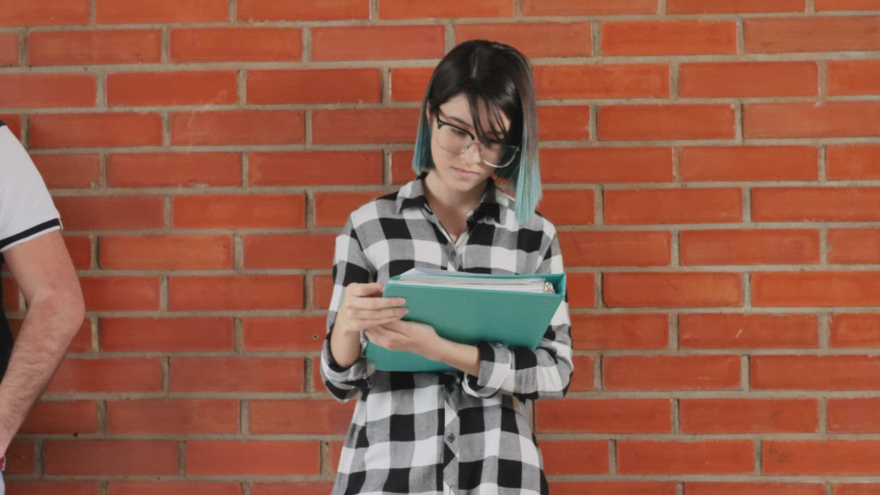 Two young people studying standing leaning against a wall in their ...