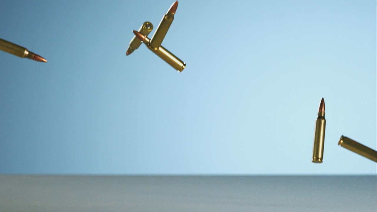 Bullets falling and bouncing on a blue background - Free Stock Video
