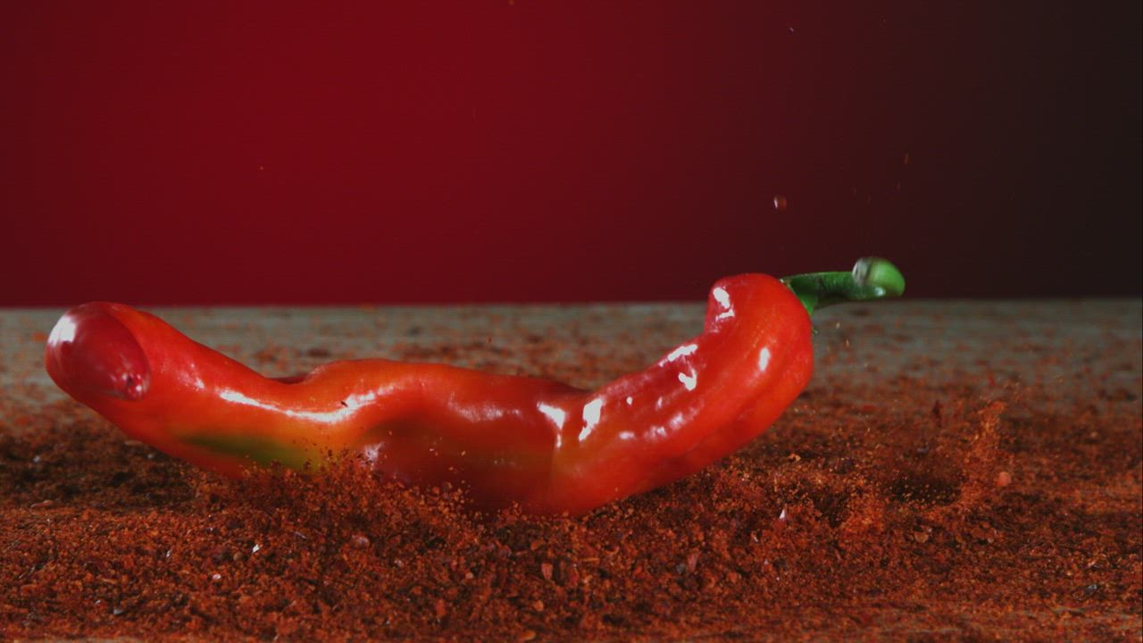 Big red pepper falling into red powder - Free Stock Video
