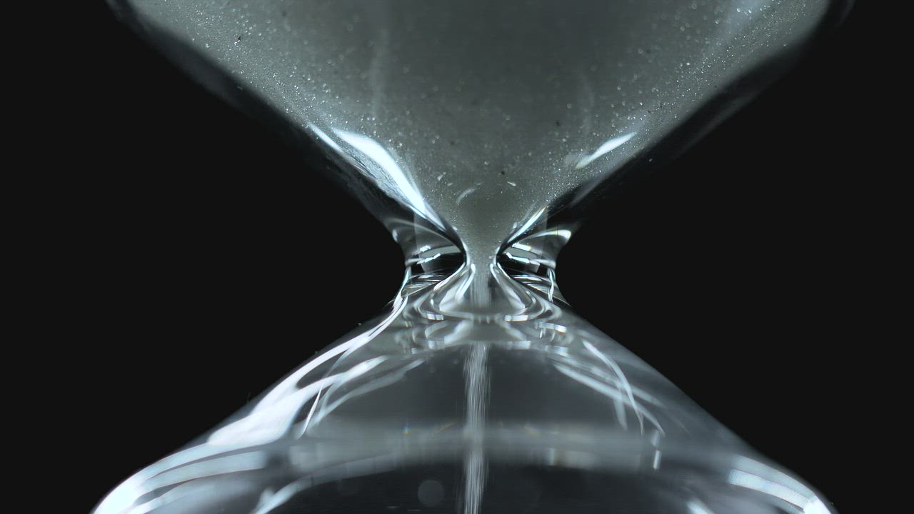 Glass hourglass close up on a black background - Free Stock Video