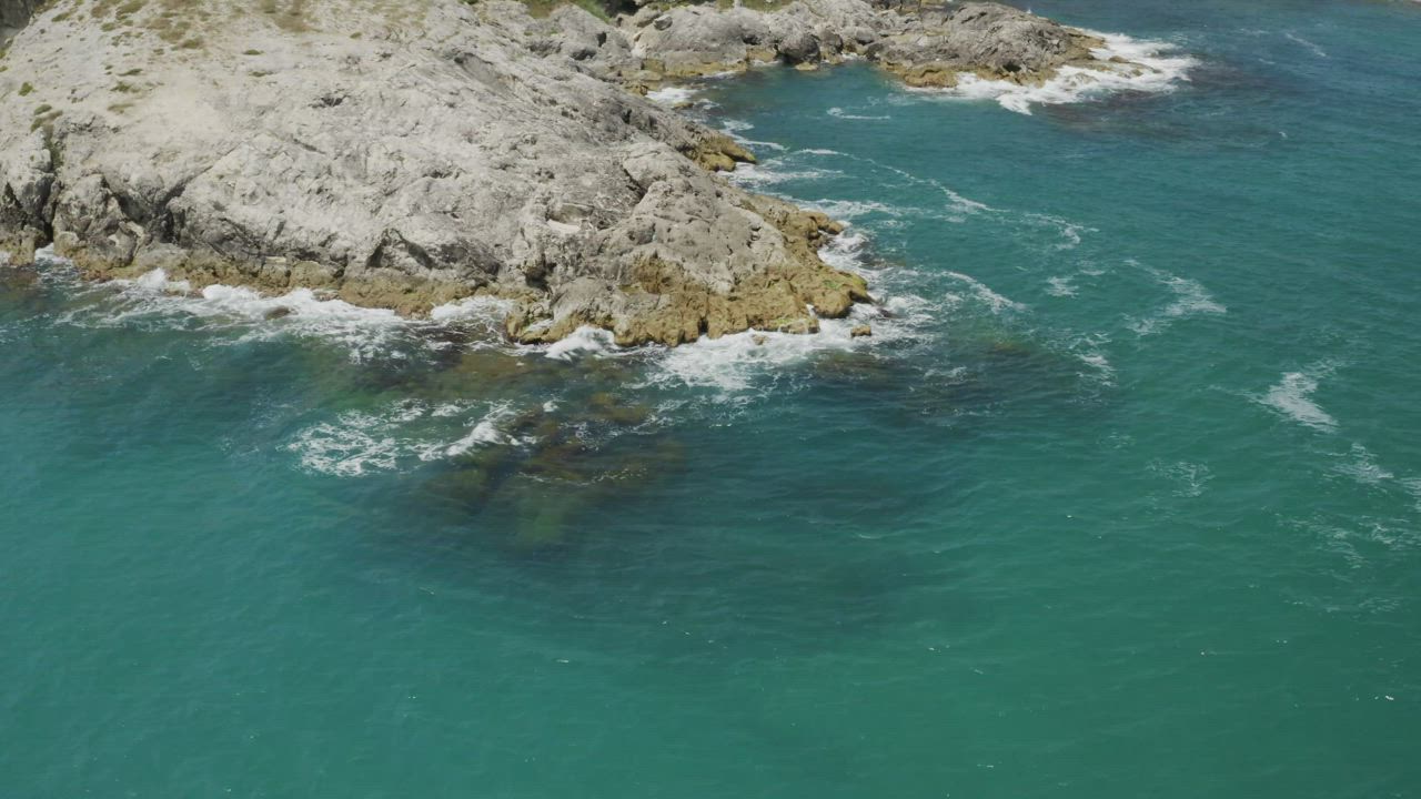 Clean coastal water breaking against rocks - Free Stock Video