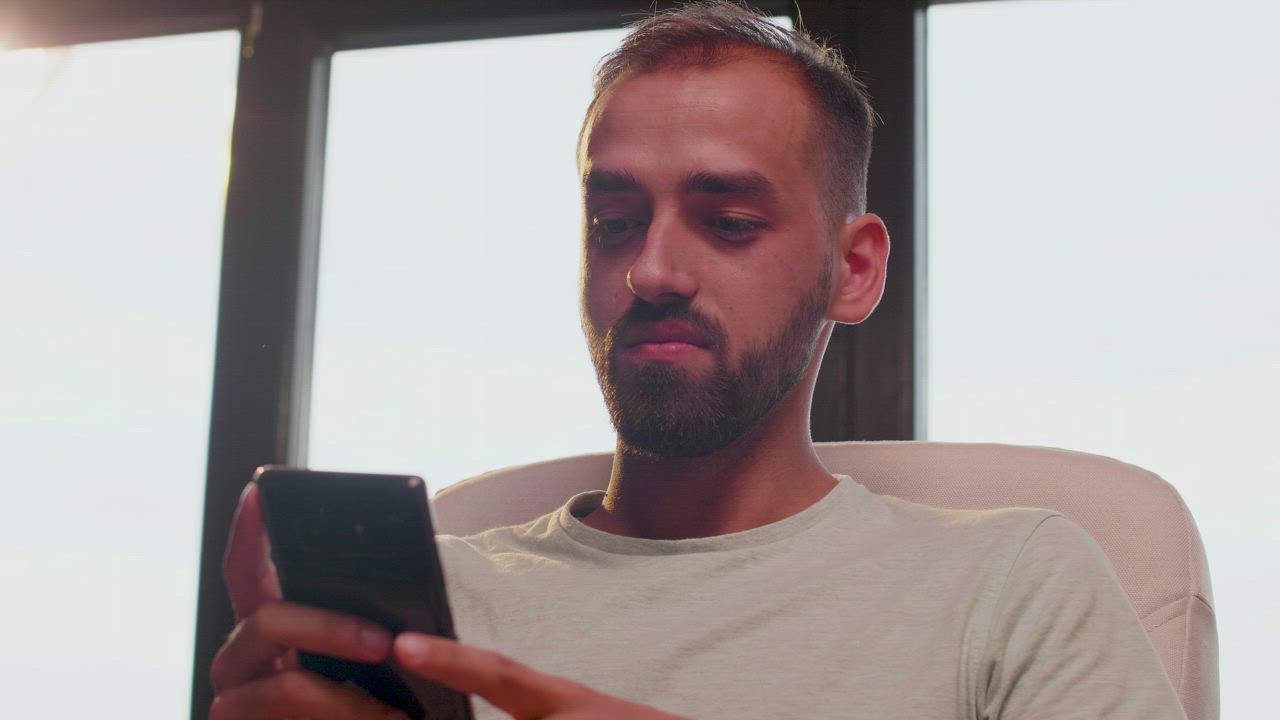 Man looking at his cell phone while smiling - Free Stock Video