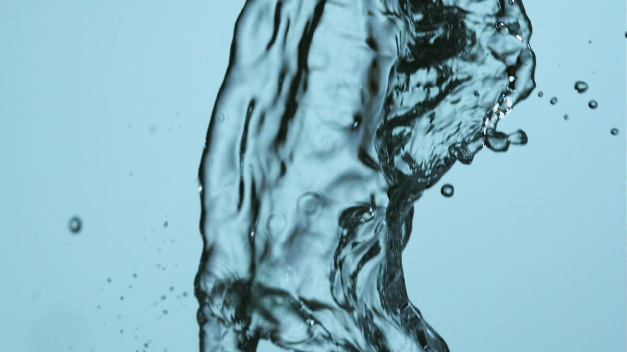 Water falling in slow motion on a blue background - Free Stock Video