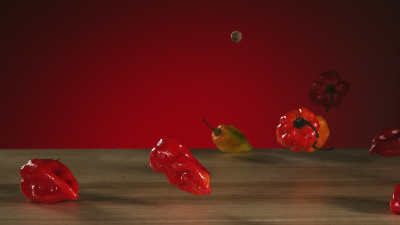 Peppers falling and bouncing on a wooden table - Free Stock Video
