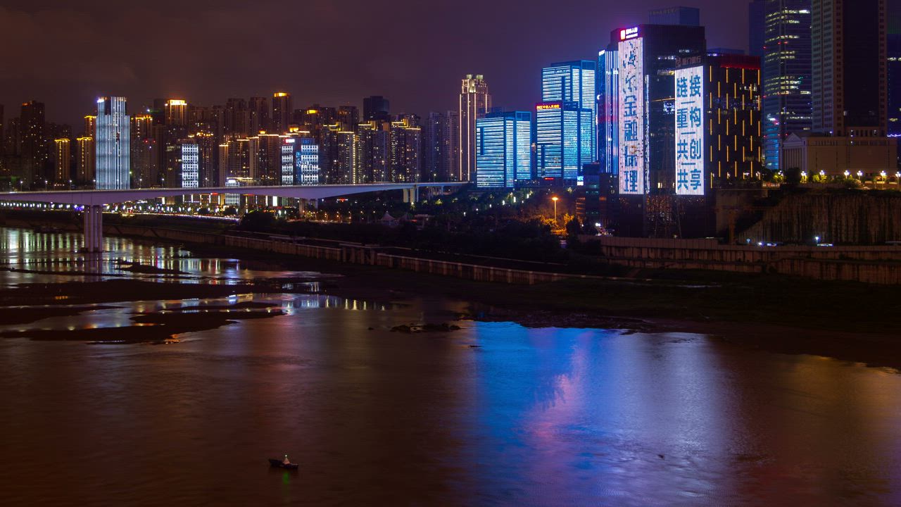 Illuminated and flashing buildings by the river - Free Stock Video