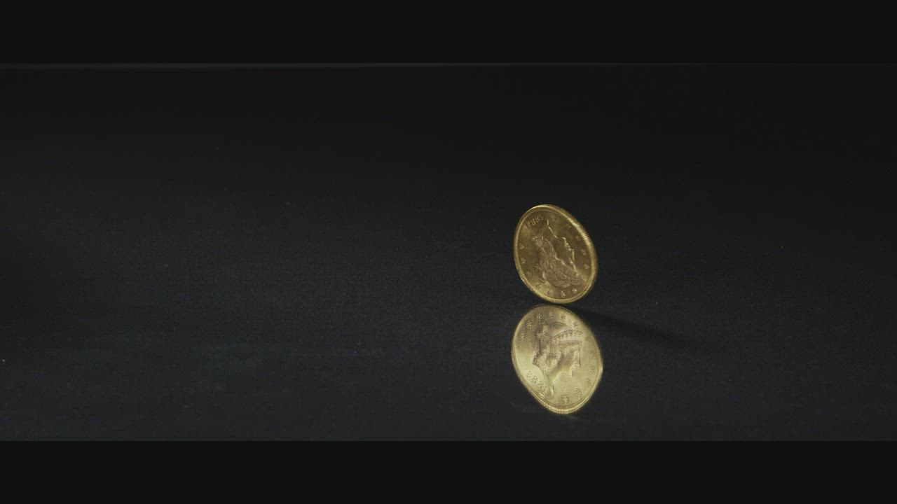 Spinning coin on a reflective surface - Free Stock Video