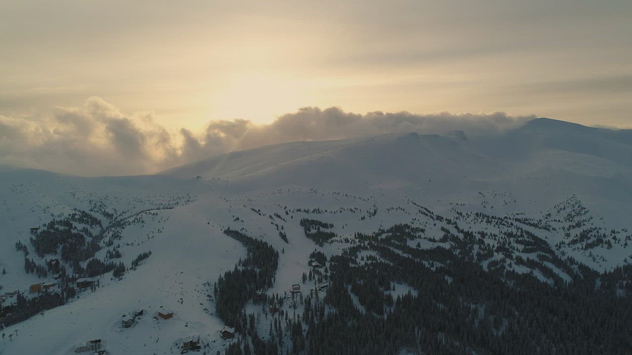 Snowy mountain with pine trees and mist overhead - Free Stock Video