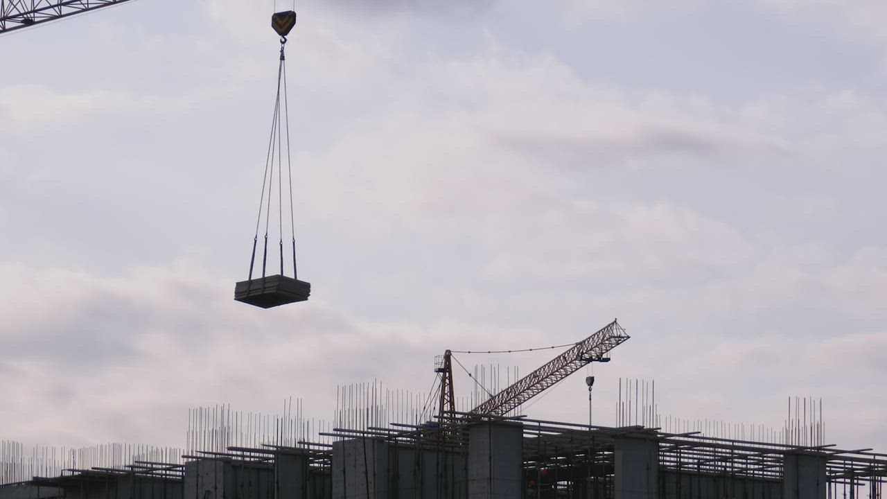 Tower crane with load on a construction site - Free Stock Video