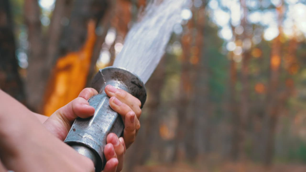Holding a fire hose throwing water - Free Stock Video
