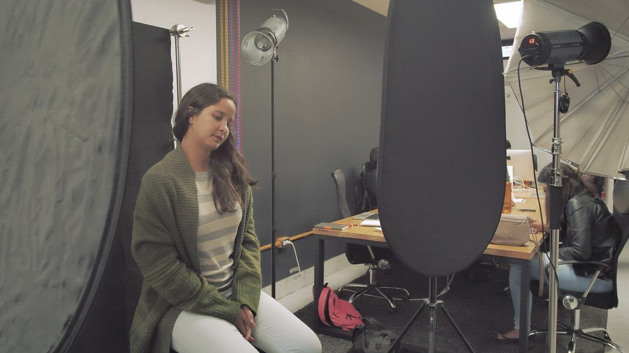 Woman sitting in a photo studio smiles - Free Stock Video