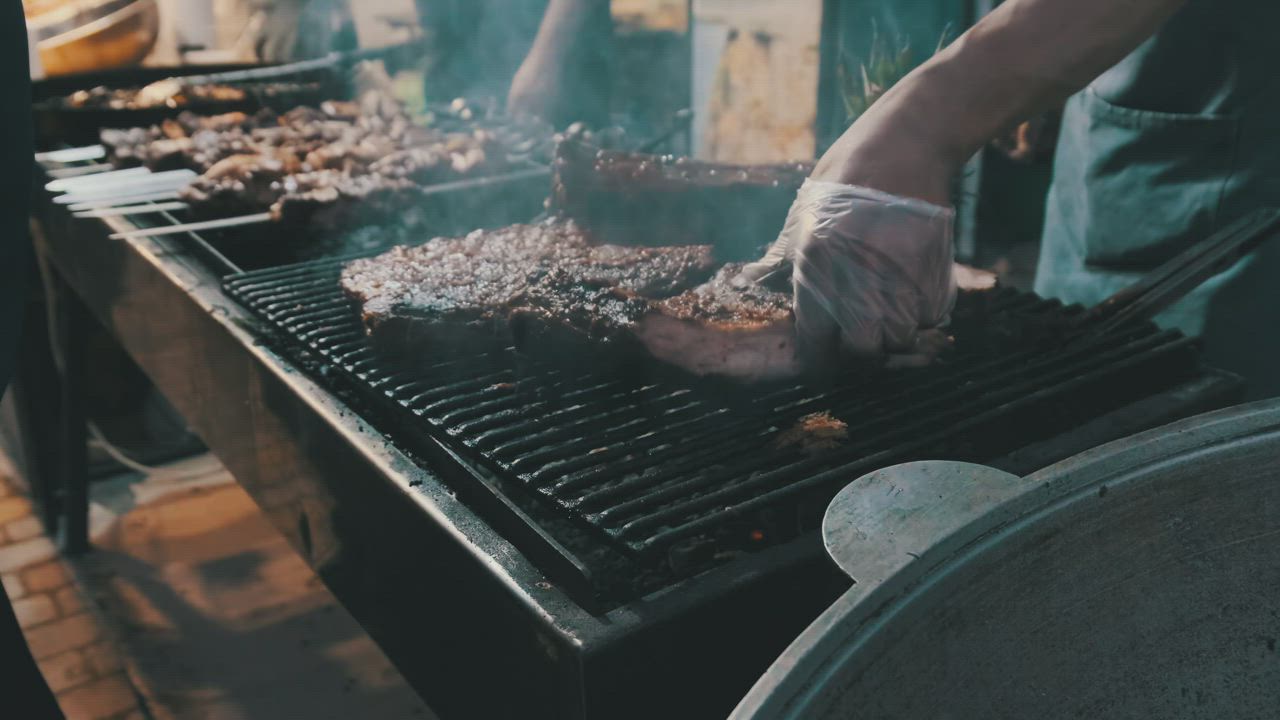 Person cooking cuts of meat on the grill - Free Stock Video