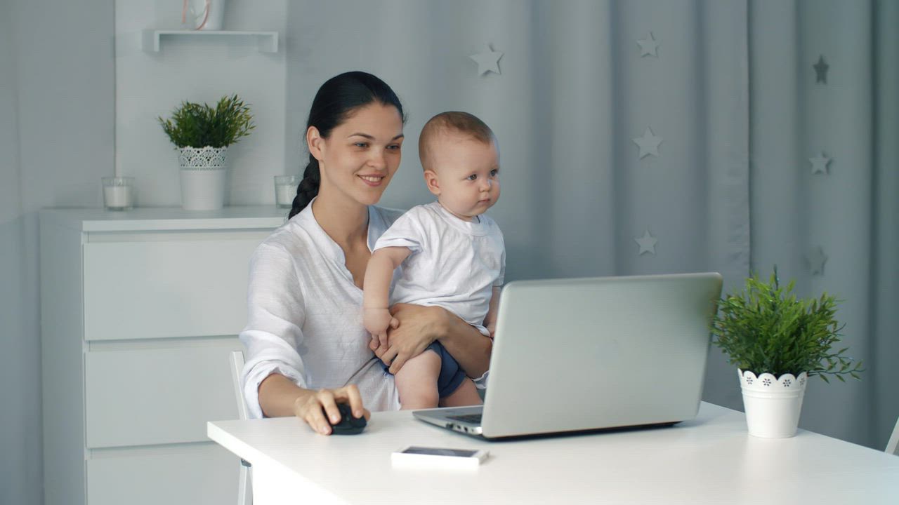 Mom on her computer while taking care of her son - Free Stock Video