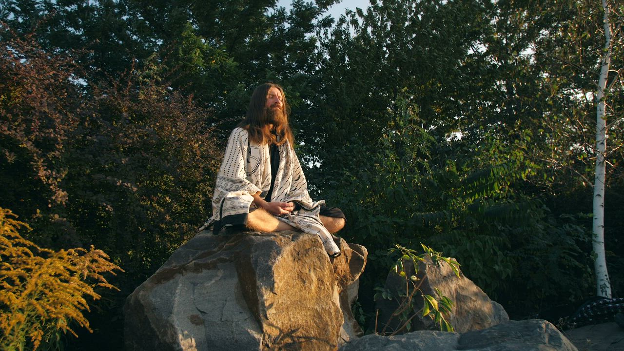 Spiritual man meditating on a rock in nature - Free Stock Video