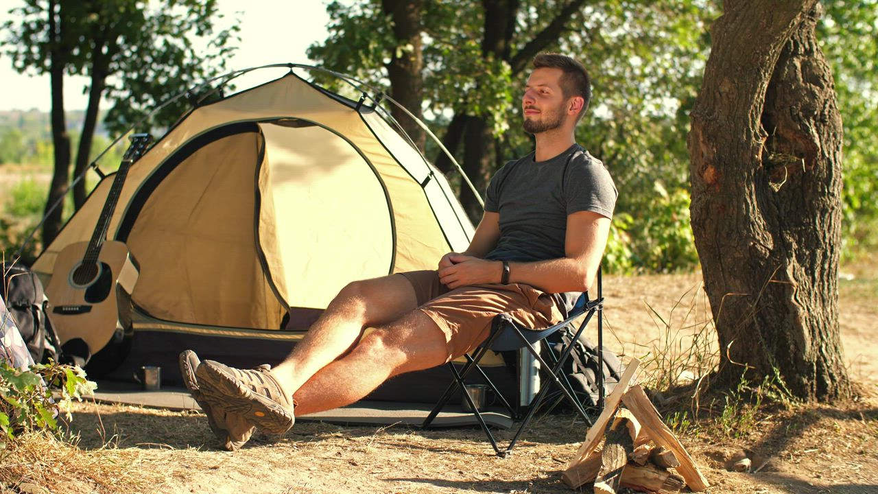 Man relaxing in his camp in nature - Free Stock Video