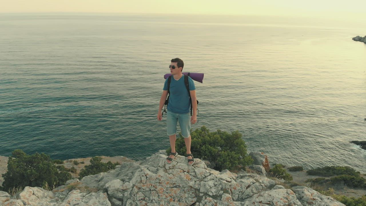 Man standing on a cliff facing the sea - Free Stock Video