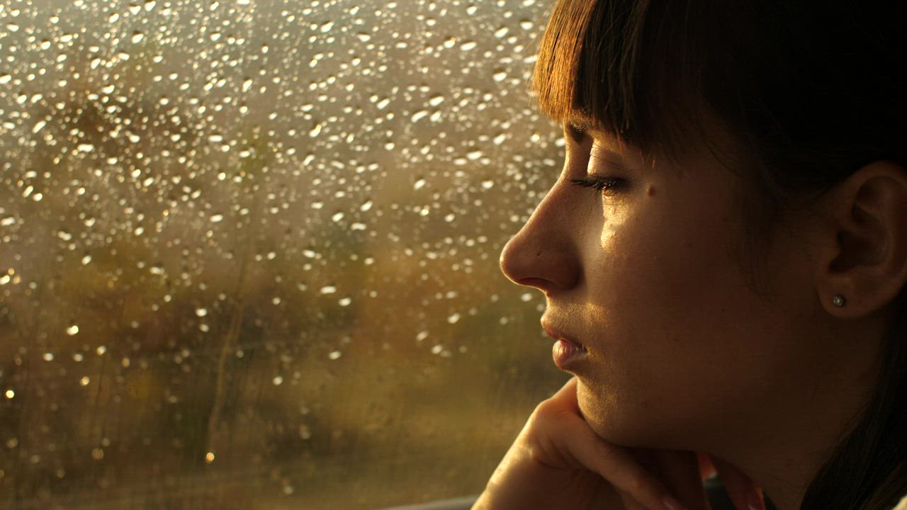 Pensive woman looking out of a window on a rainy day - Free Stock Video