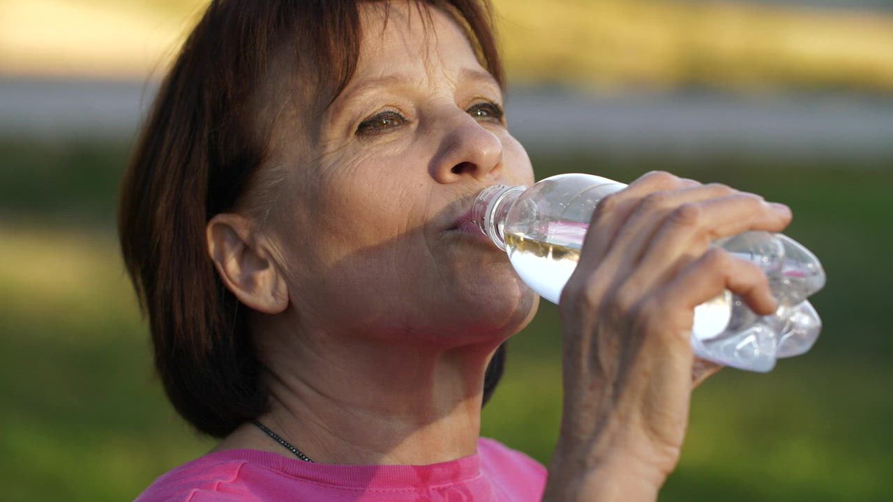 Old woman drinking water from a bottle - Free Stock Video