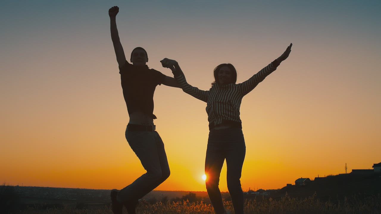 Silhouette of a couple jumping in the sunset - Free Stock Video