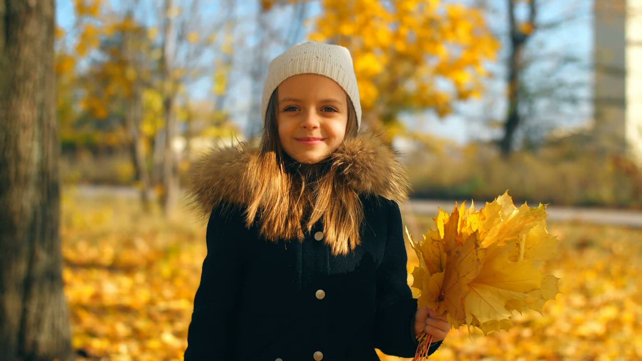 Happy girl with autumn leaves in a park - Free Stock Video
